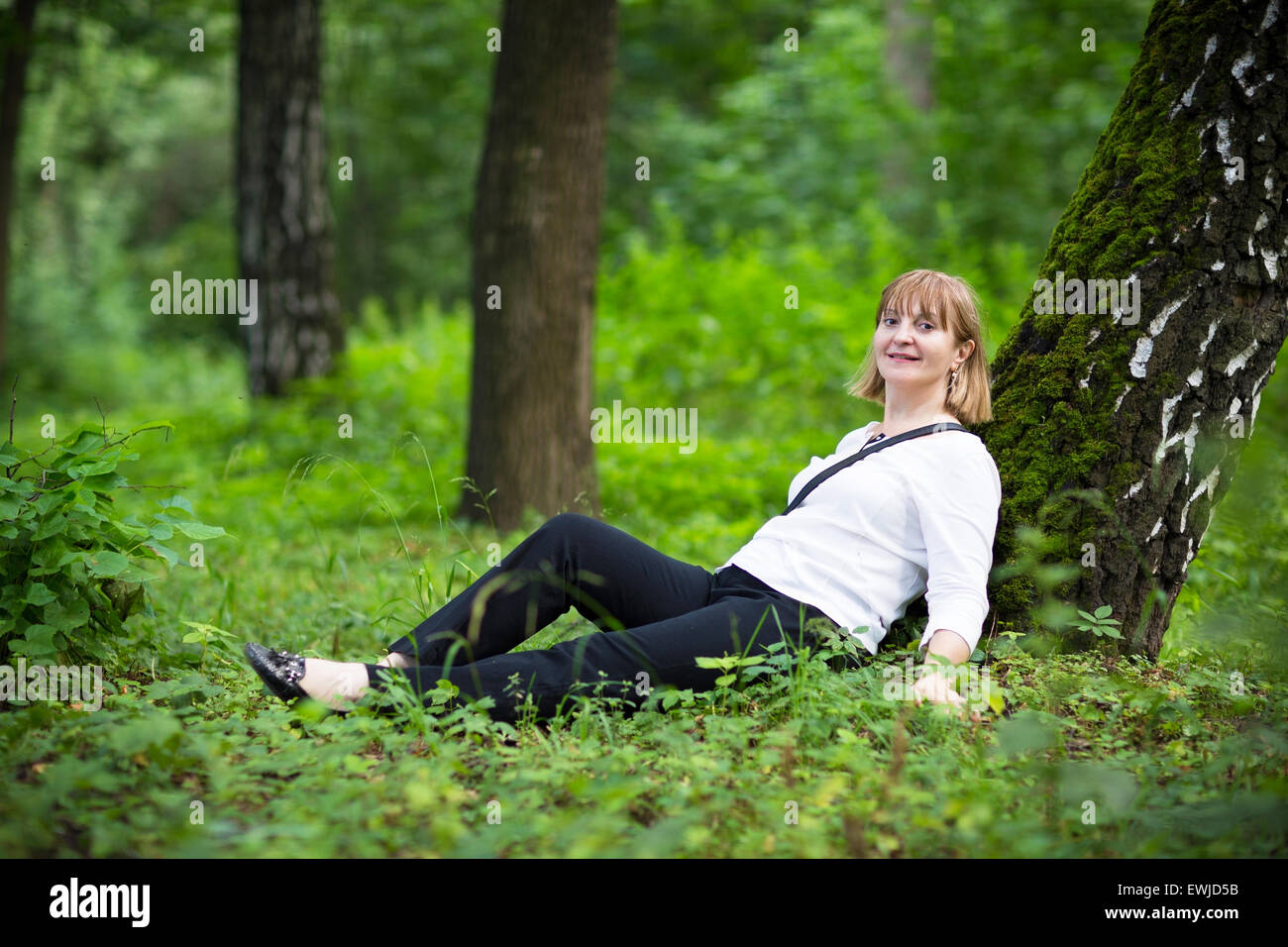 Beautiful woman relaxing under a big old tree Stock Photo - Alamy