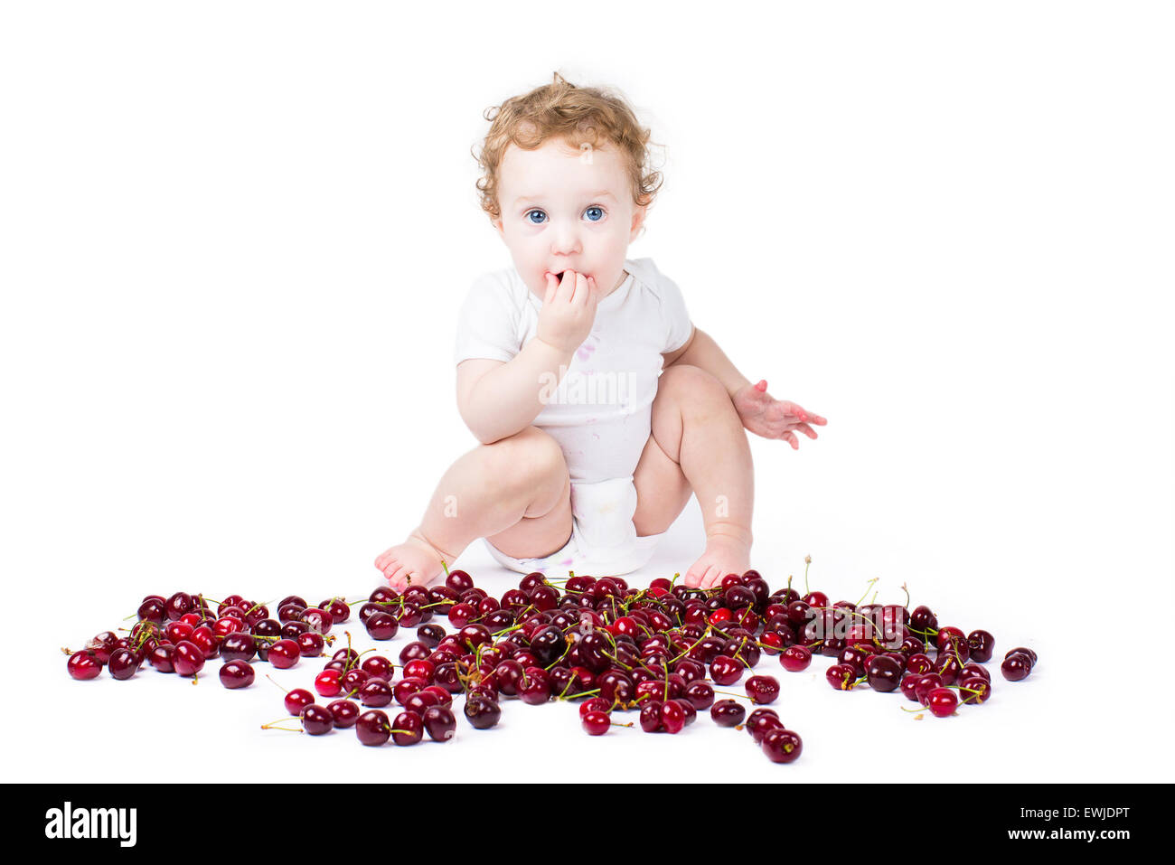 Cute baby girl eating red cherry Stock Photo - Alamy