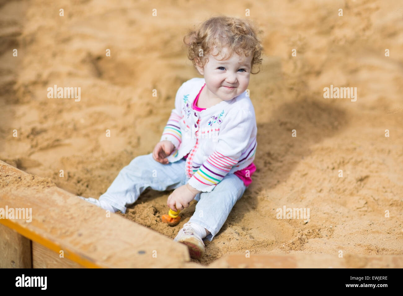 Cute little baby girl digging in sand on a playground Stock Photo - Alamy