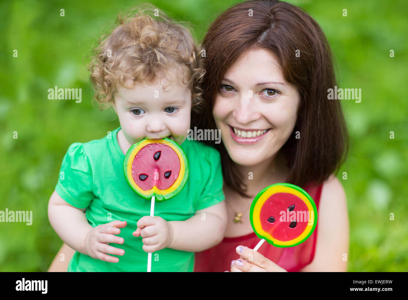 Young beautiful mother and her adorable curly baby daughter eating ...