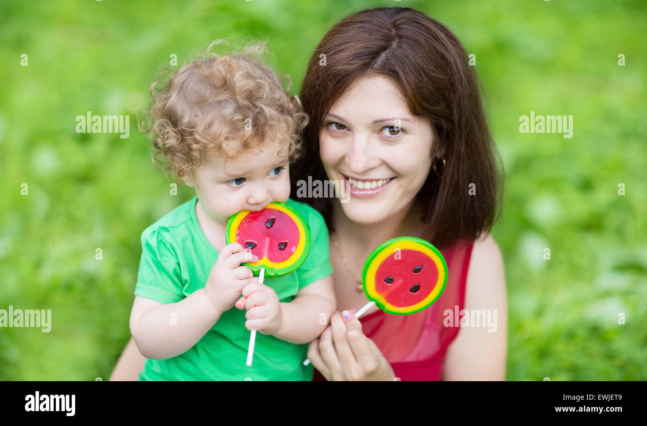 Young beautiful mother and her adorable curly baby daughter eating ...