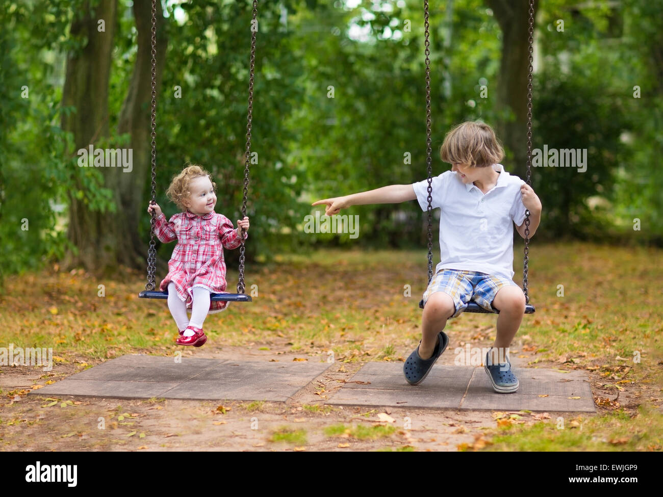 Brother and little baby sister playing together on a swing on a ...