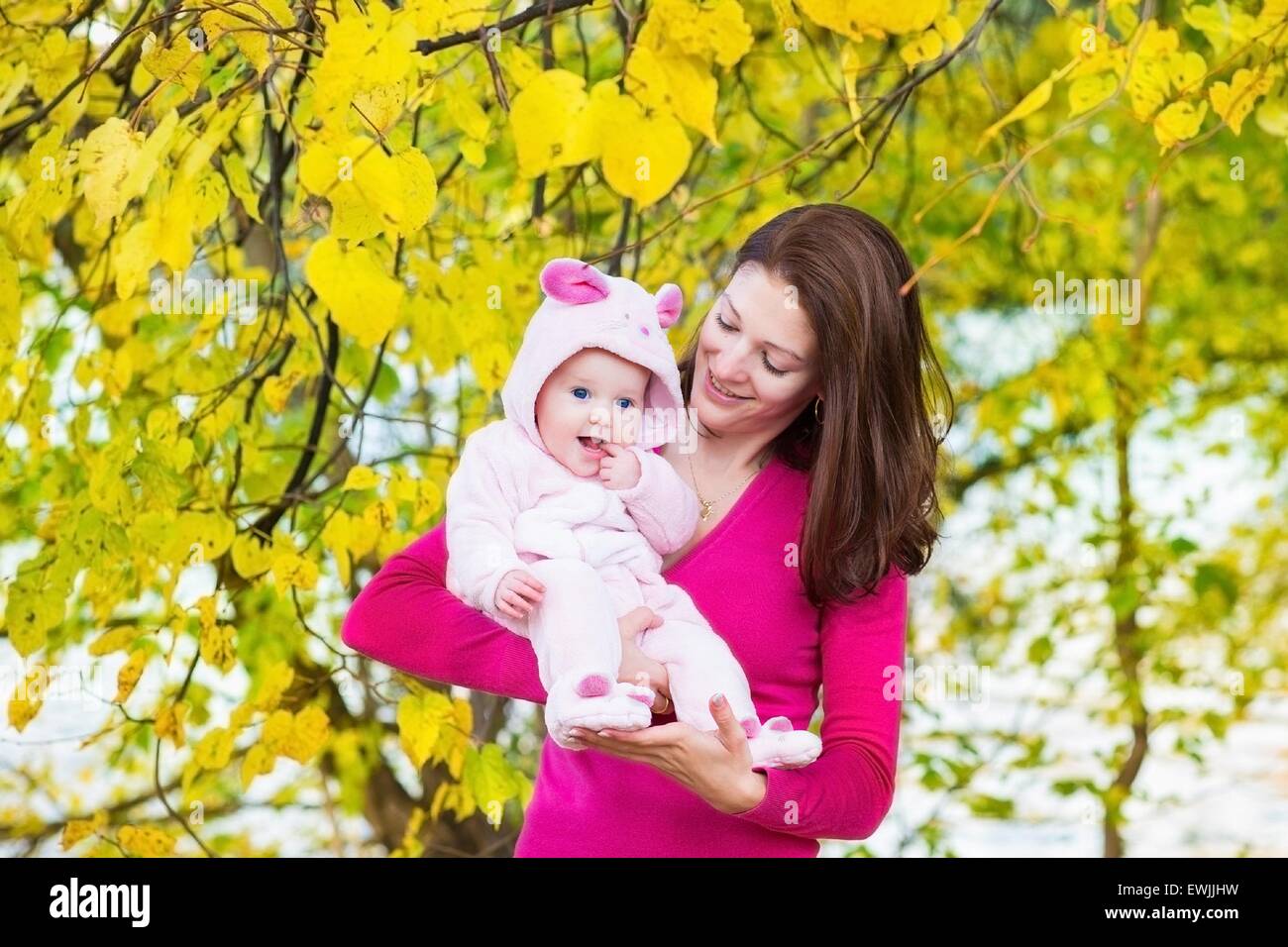 Young mother holding her baby catching falling autumn leaves Stock ...