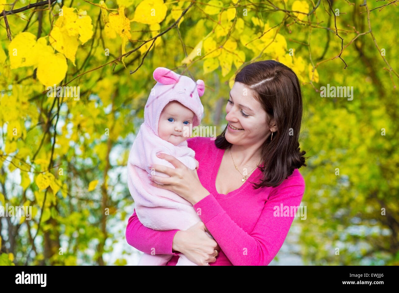 Young mother holding her baby catching falling autumn leaves Stock ...
