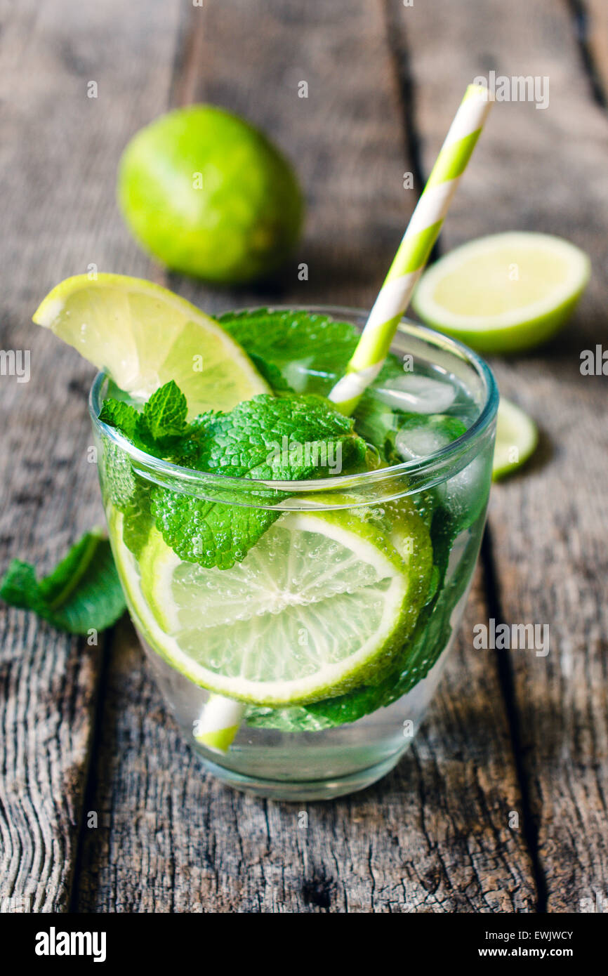 Cold soda water with lime and herbs in glass on wooden background ...
