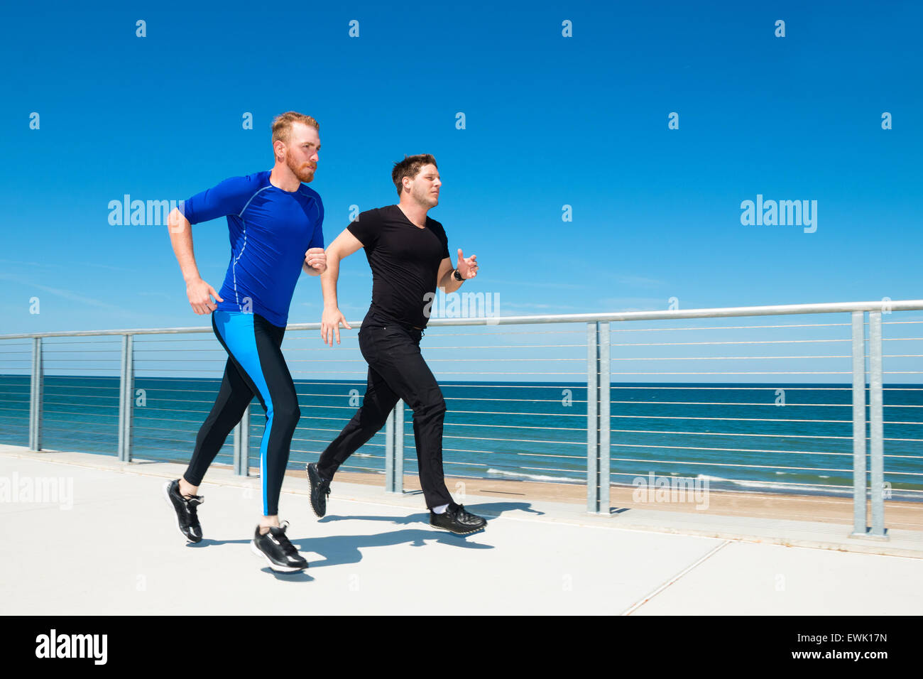 Two men running or jogging at a beachside park Stock Photo - Alamy