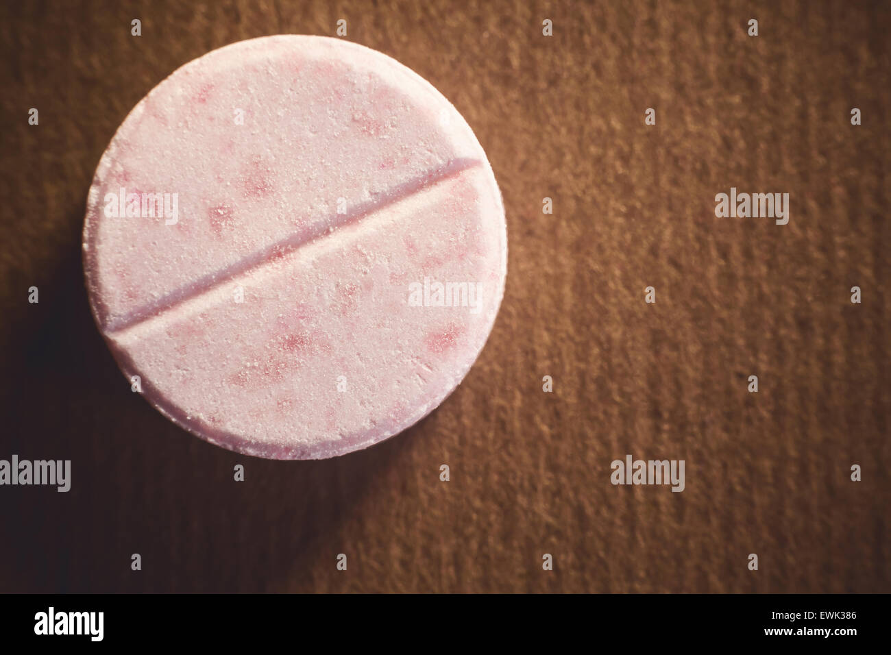 Macro view of a pink pill, textures details, brown background in blur ...