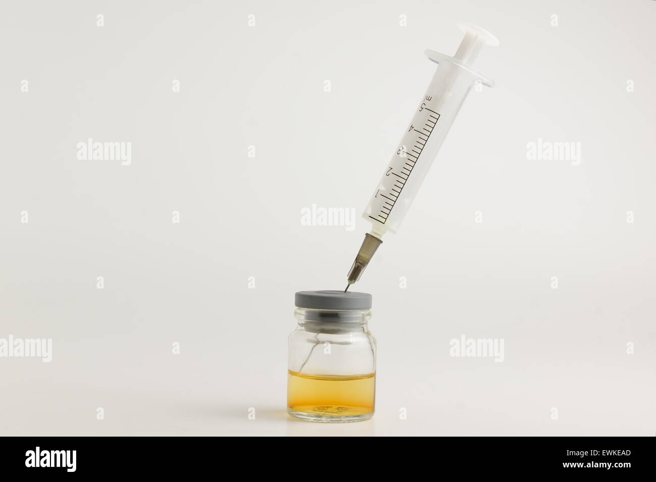 a syringe with a sharp needle and ampule with a drug on a white ...