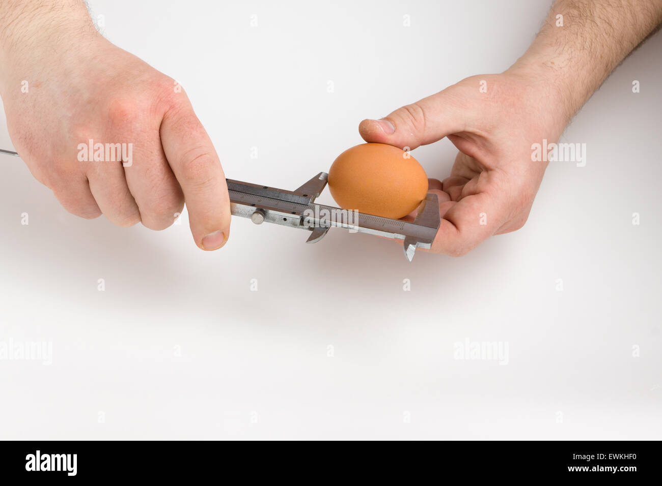 two hands with the measuring tool on a white background measure egg ...