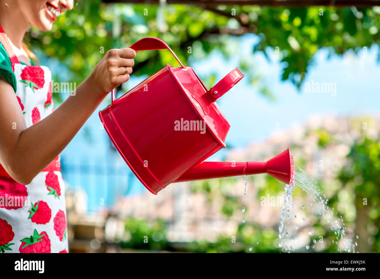 Pouring with a pink watering can Stock Photo - Alamy
