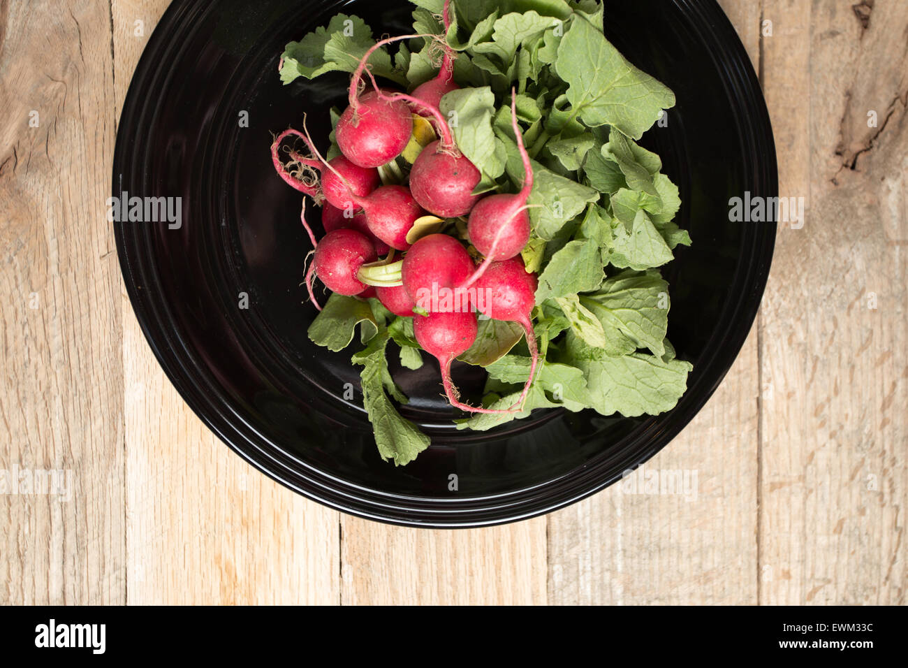 Red radishes in black bowl on weathered wood background Stock Photo - Alamy