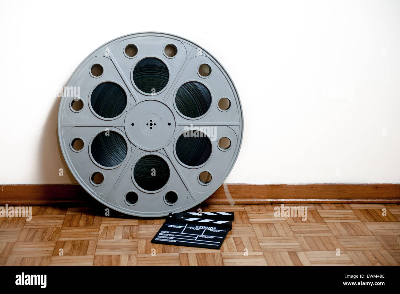 35 mm cinema movie roll with clapper on wooden floor and white wall ...
