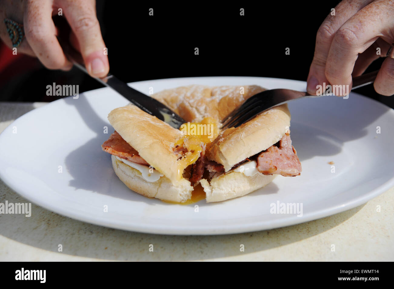 Woman eating a freshly made bacon and egg bap for breakfast Stock Photo ...