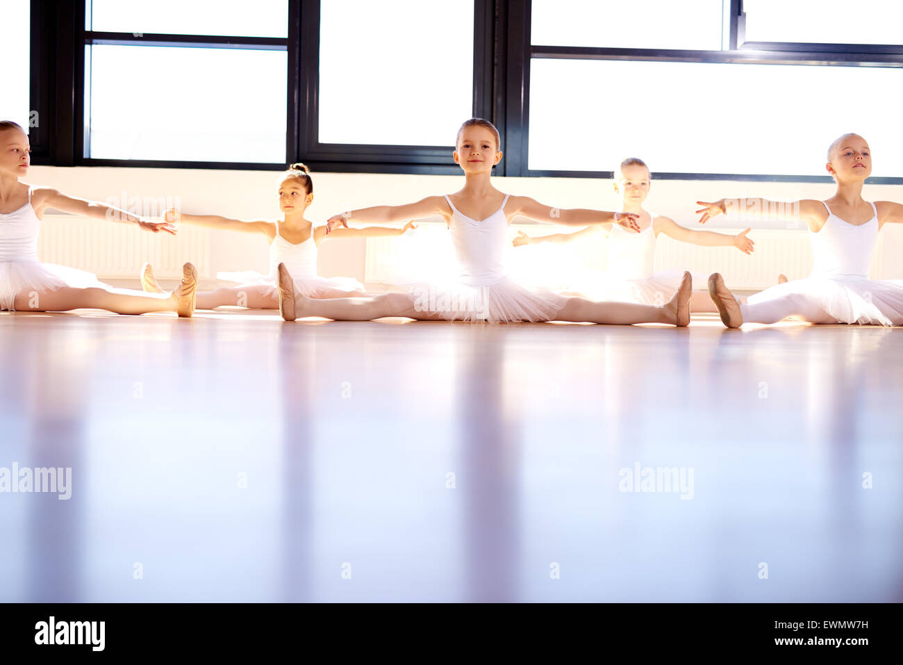 Group of little girls in a ballet studio wearing white tutus sitting on ...