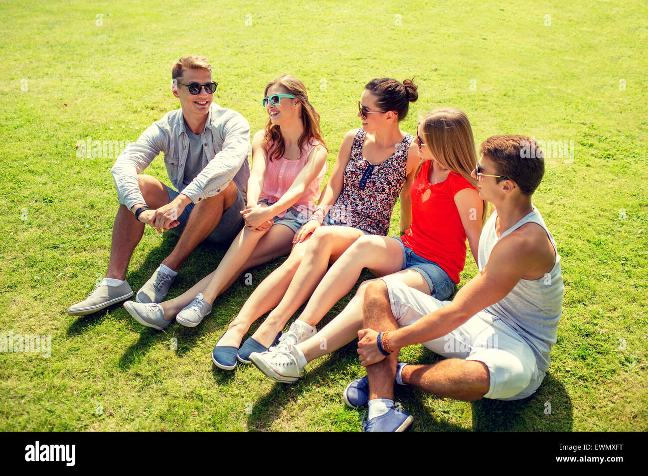 group of smiling friends outdoors sitting in park Stock Photo - Alamy