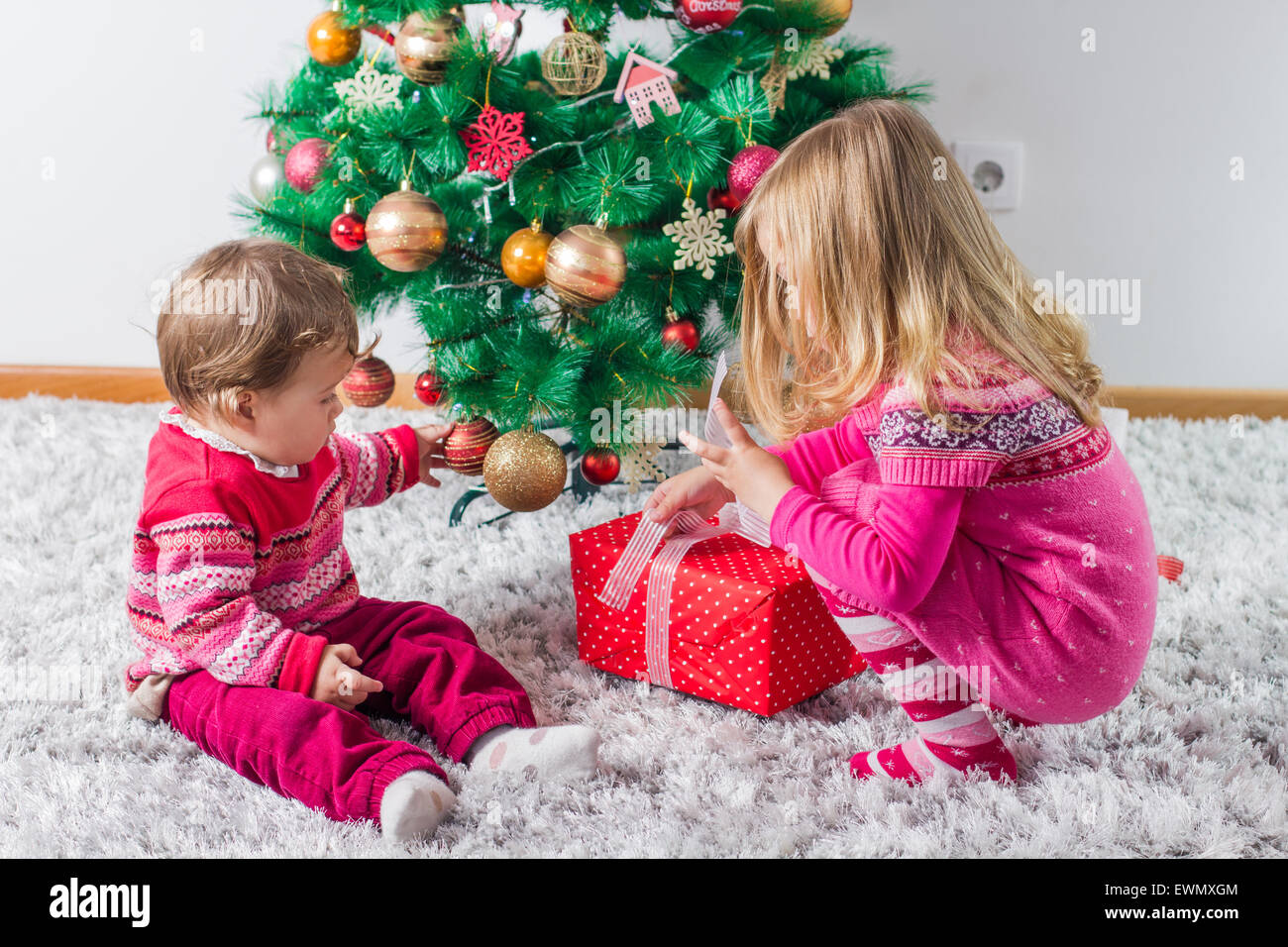Charming happy children open Christmas presents on the floor and tree ...