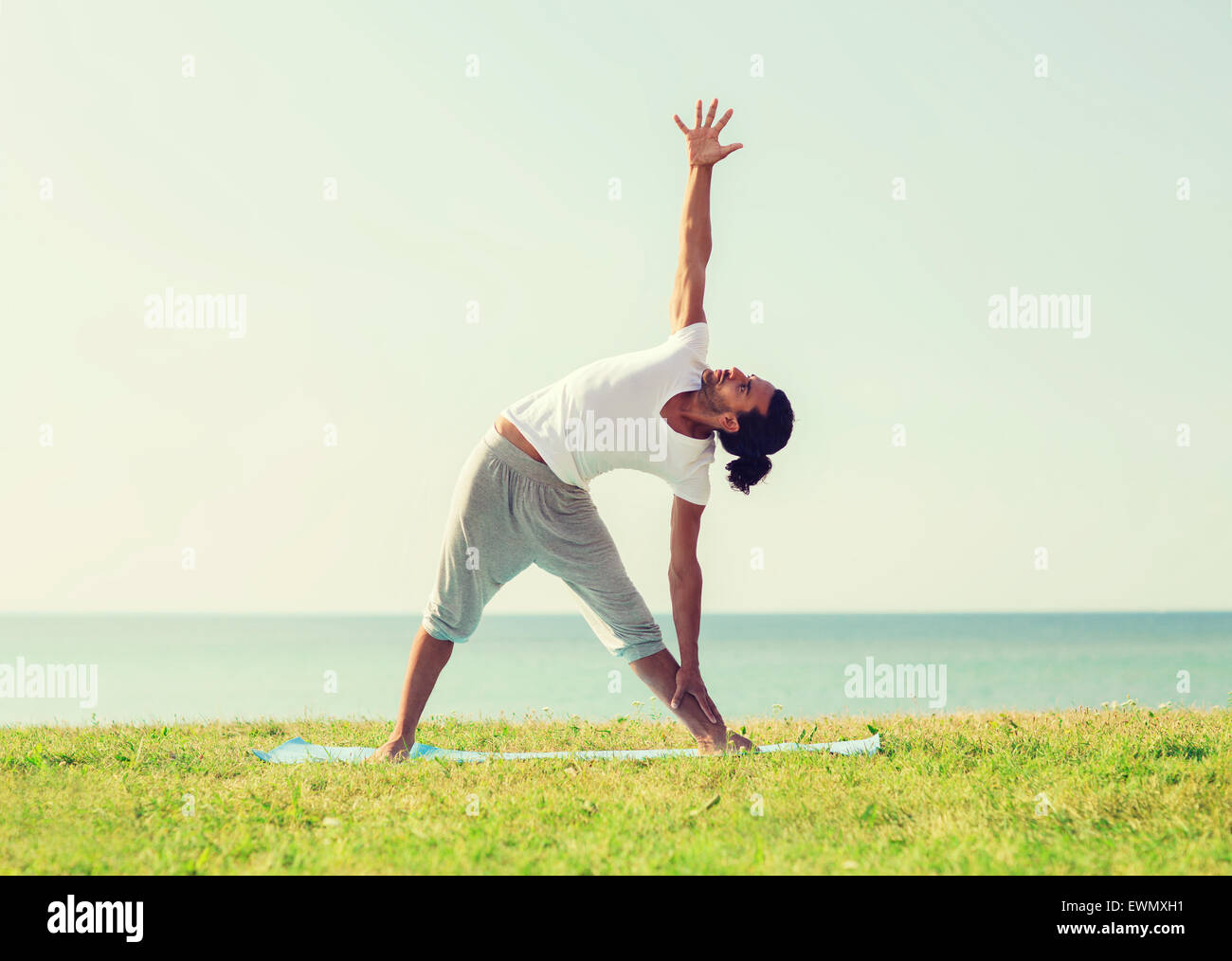 smiling man making yoga exercises outdoors Stock Photo - Alamy