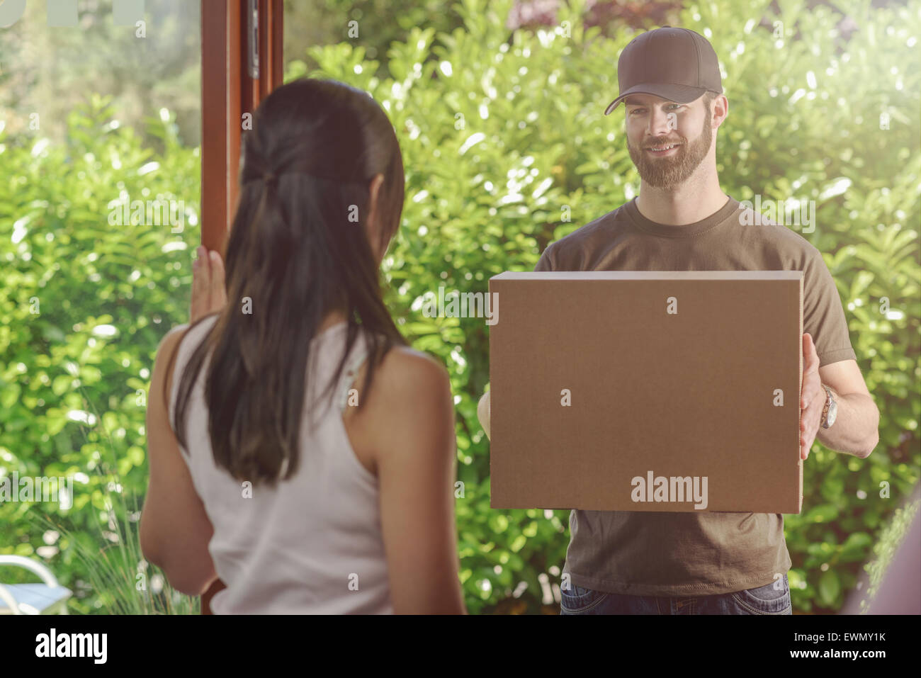 Woman answering the door to an attractive bearded deliveryman carrying ...