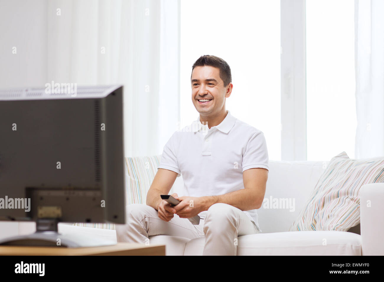 smiling man with remote control watching tv Stock Photo - Alamy