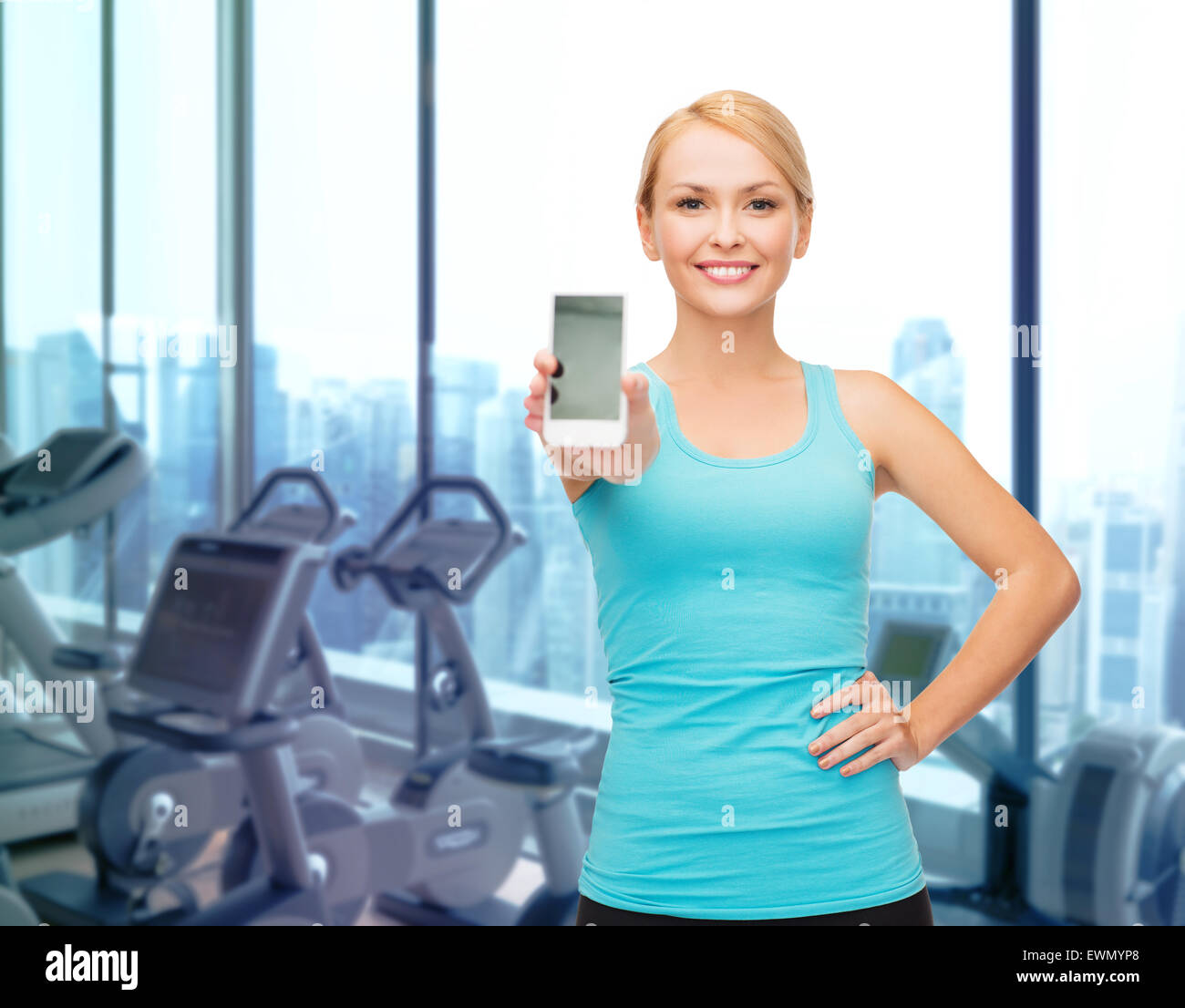 smiling sporty woman showing smartphone in gym Stock Photo - Alamy
