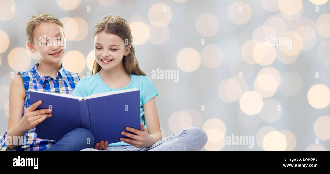 happy girls reading book over lights background Stock Photo - Alamy