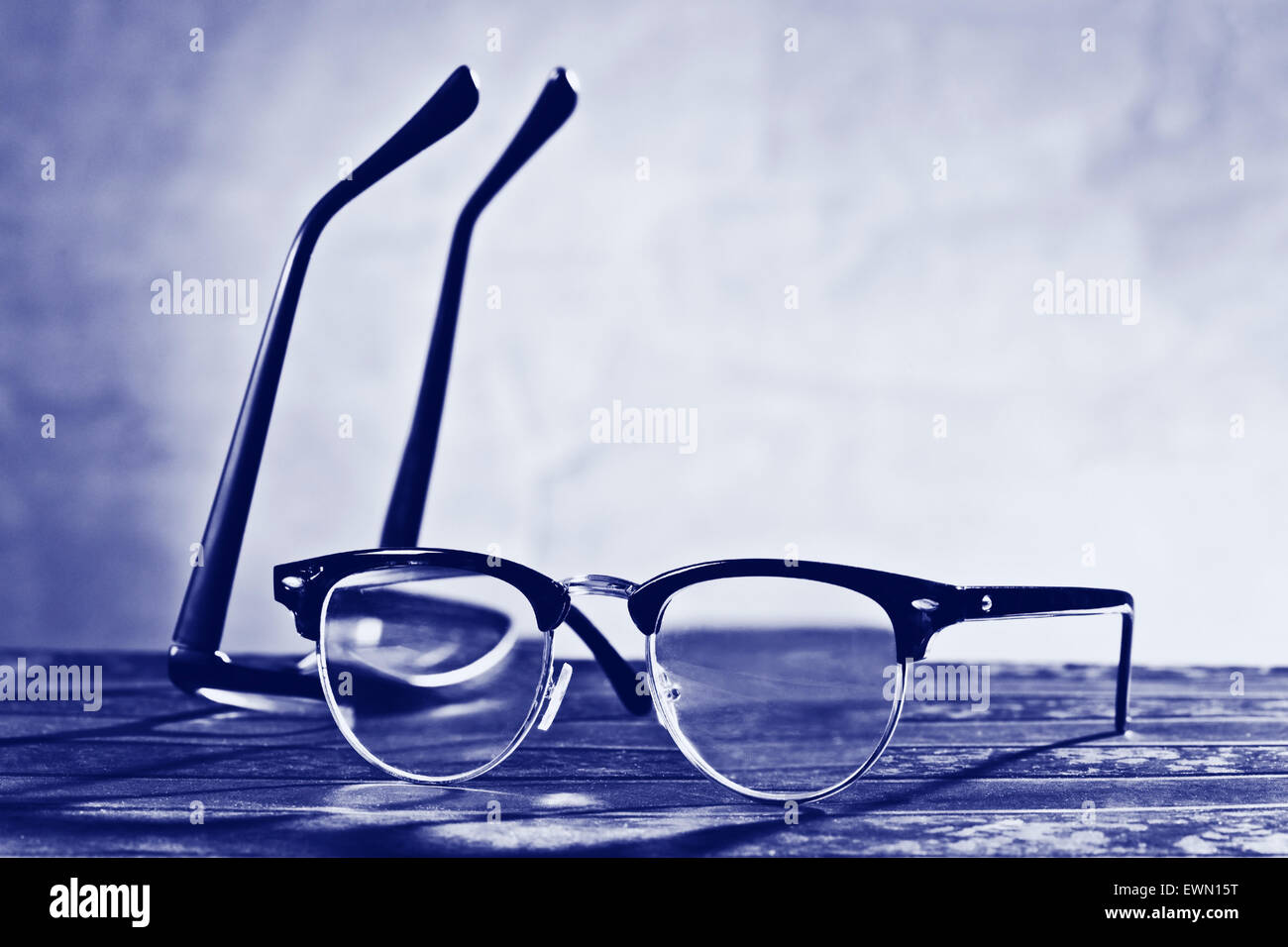 two eyeglasses on the table with blue background Stock Photo - Alamy