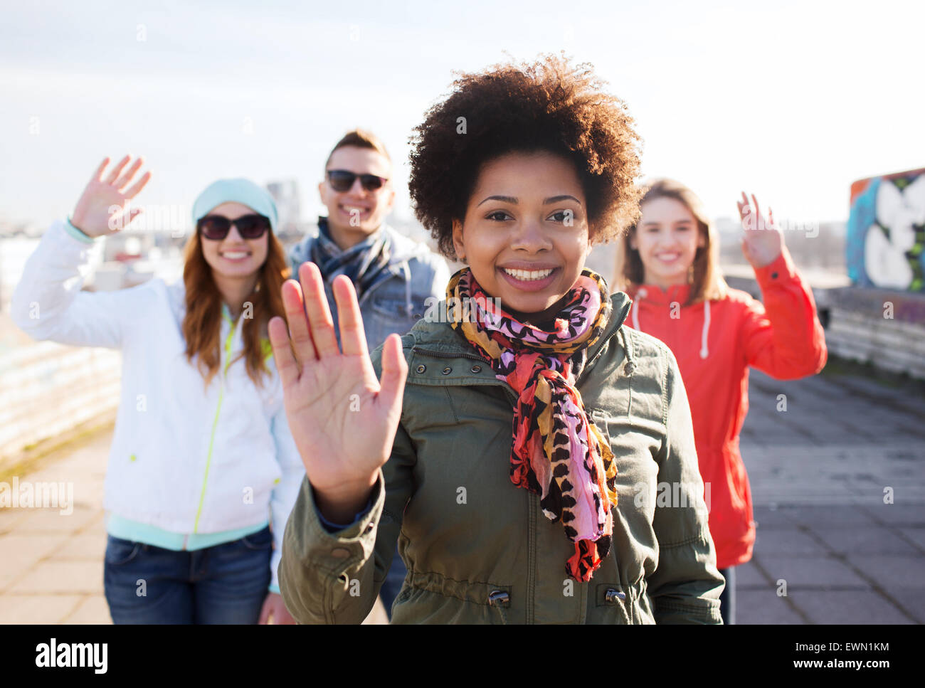 happy teenage friends waving hands on city street Stock Photo - Alamy