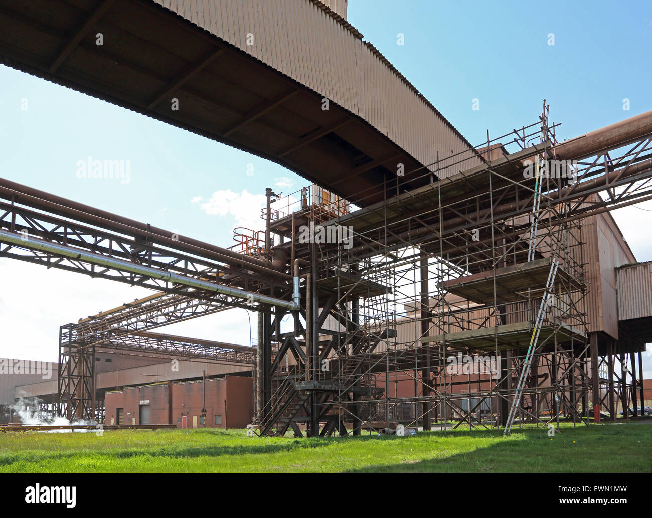 Scaffolding surrounds pipe gantries and conveyor belt housings at the ...