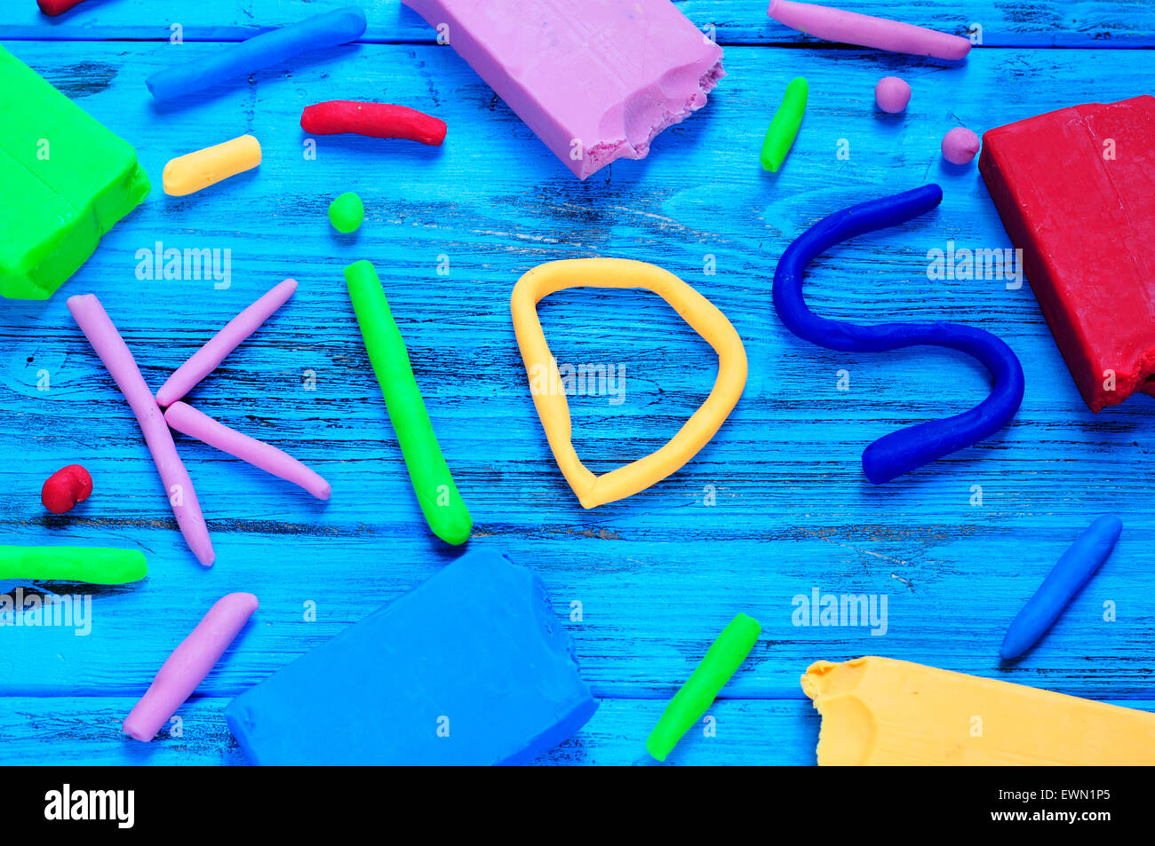 modelling clay of different colors forming the word kids on a blue ...