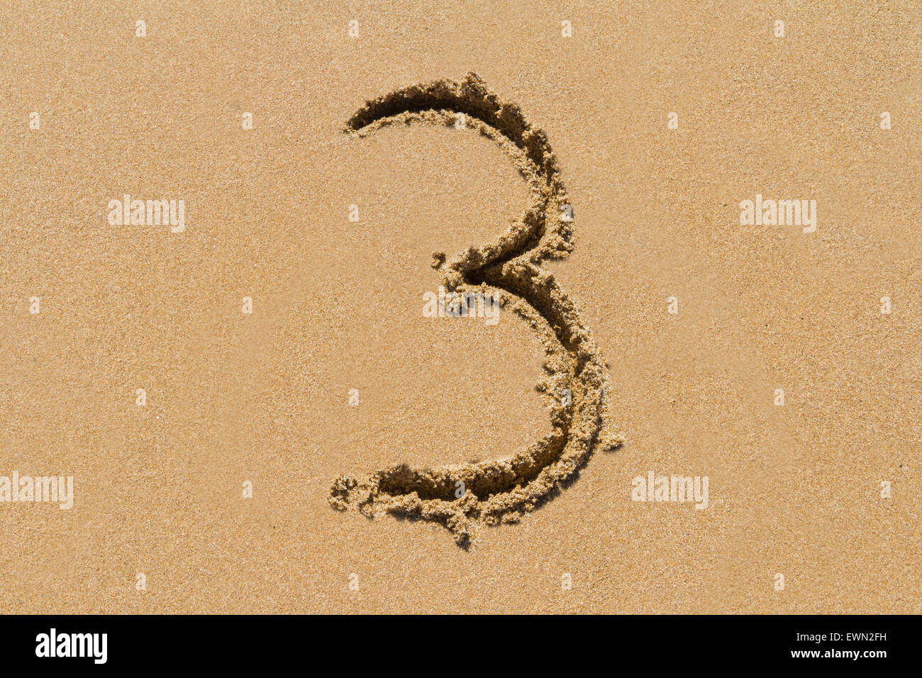 The number 3 drawn on sand at the beach, holiday concept background ...