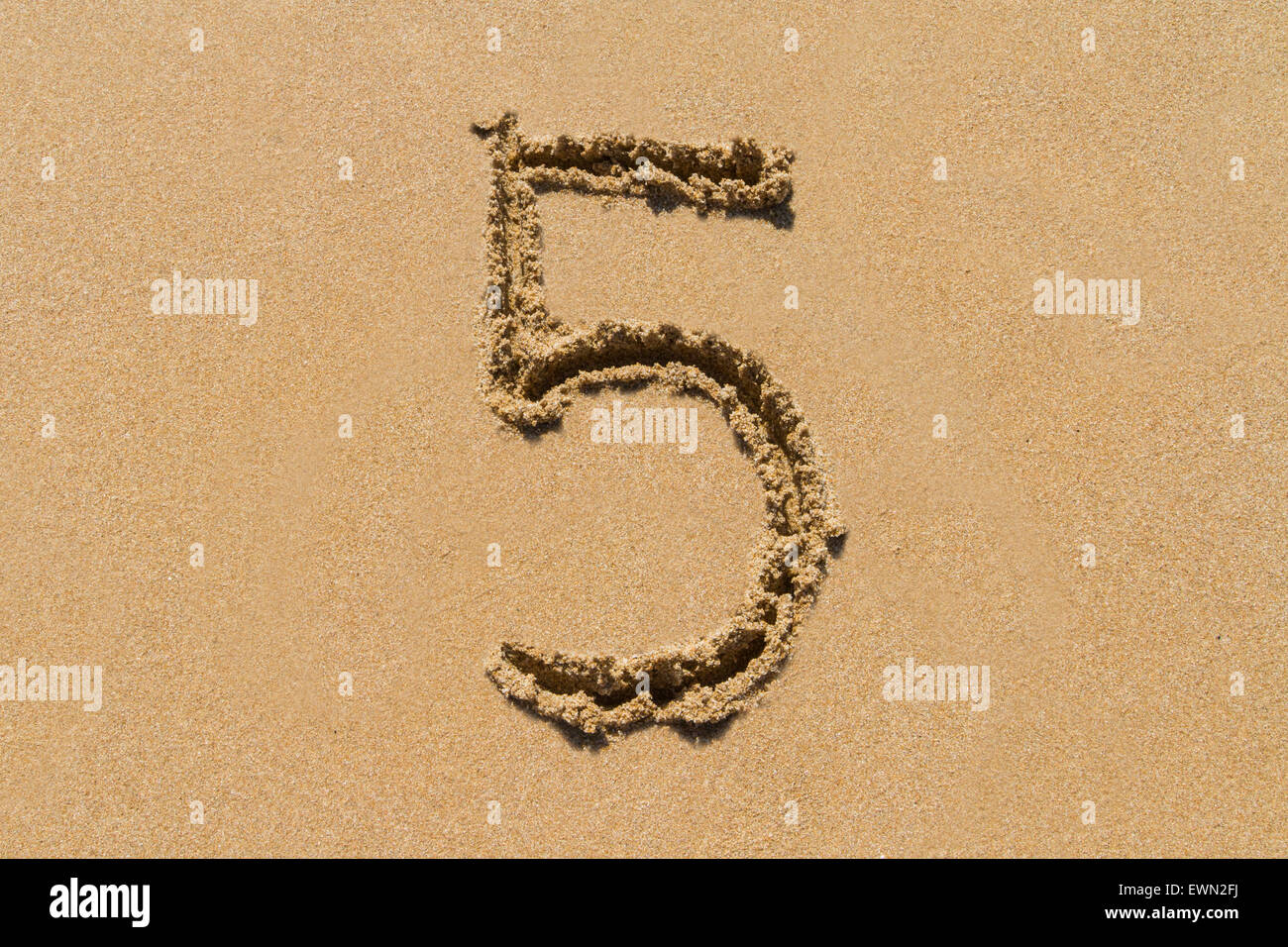 The number 5 drawn on sand at the beach, holiday concept background ...