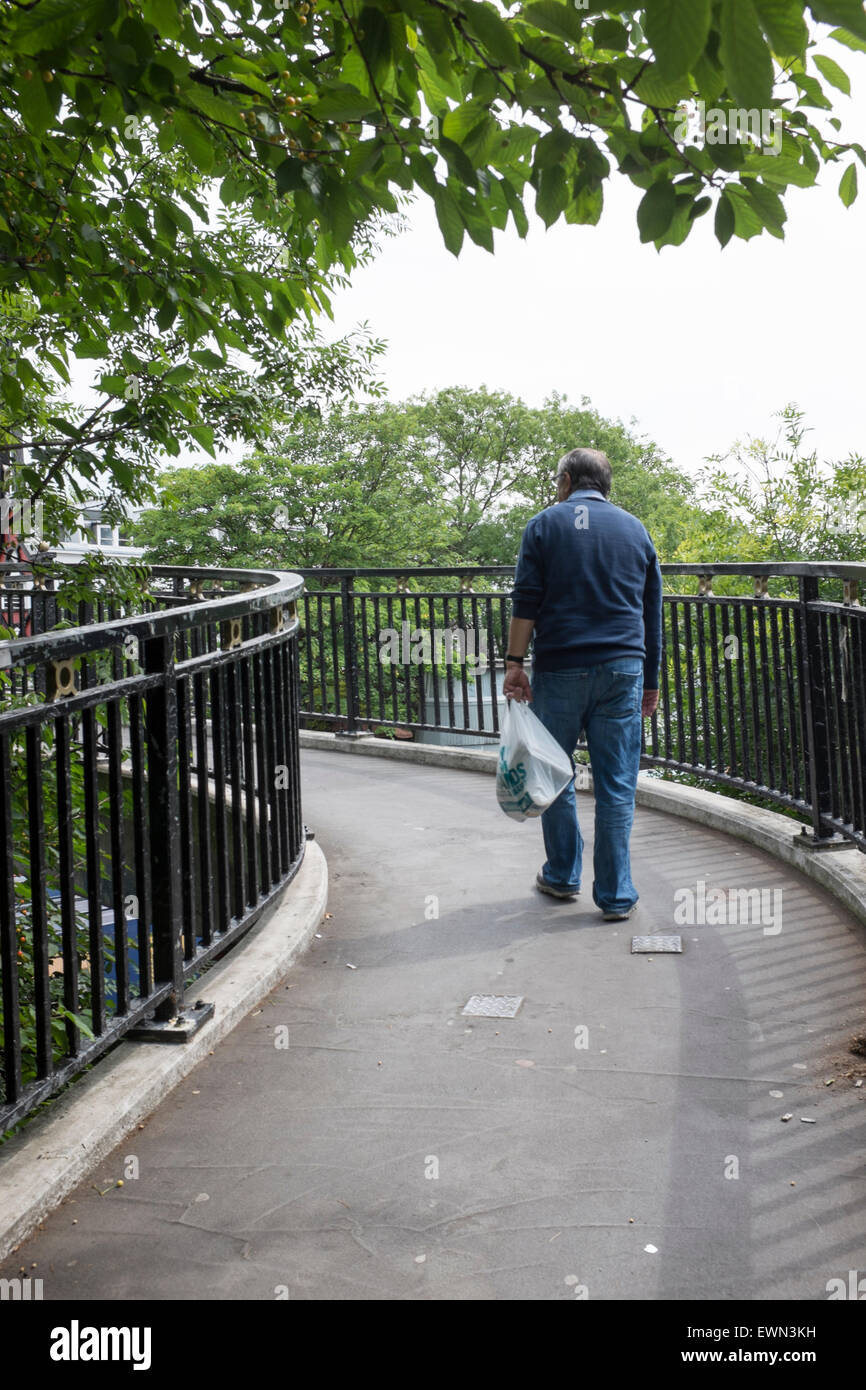 Man walking away from camera holding a plastic bag Stock Photo - Alamy