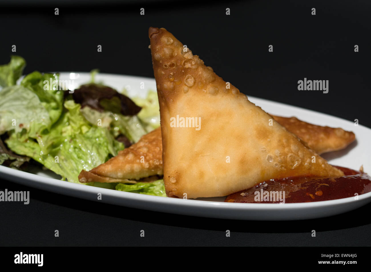 Two samosas in black background Stock Photo - Alamy