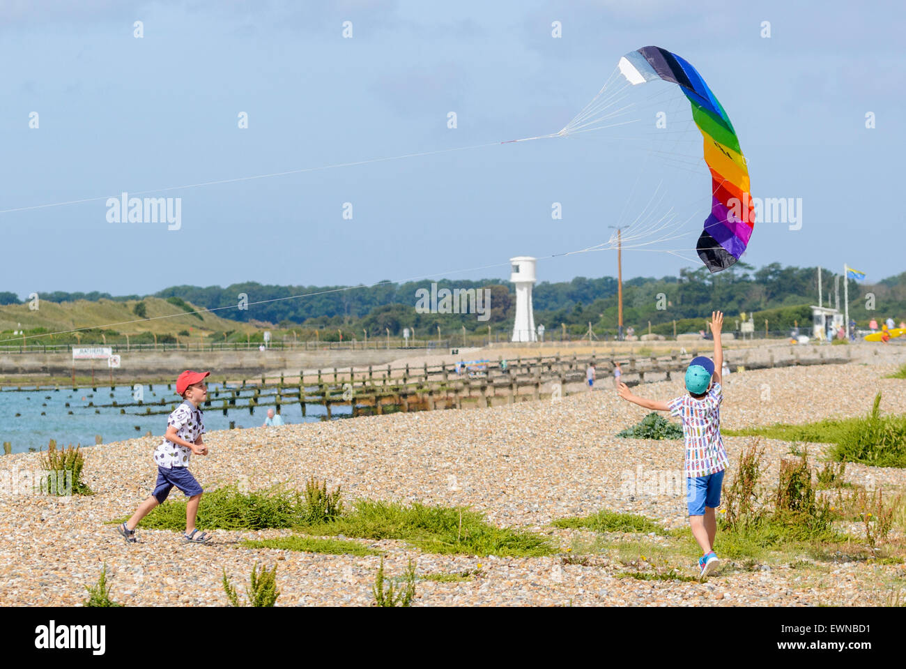 Young boys jumping up to catch a flying kite, on the beach in summer ...