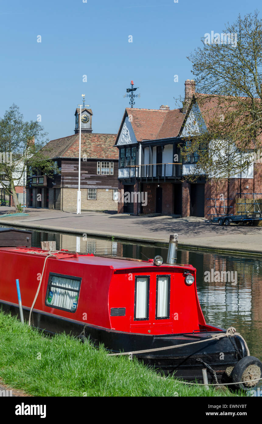 Red narrow boat in front of rowing club buildings on the River Cam ...