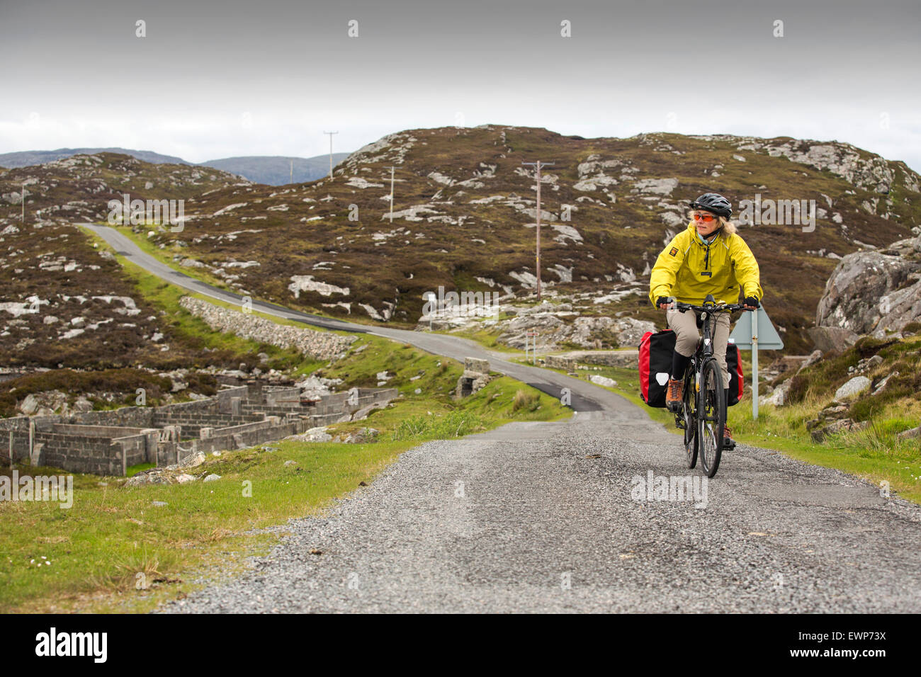 A woman cycle touring up the rugged Golden road on the East side of the ...