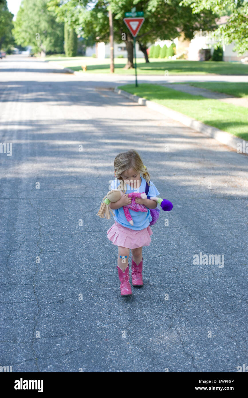 A girl walks down the street with her doll in Sandpoint, Idaho Stock ...