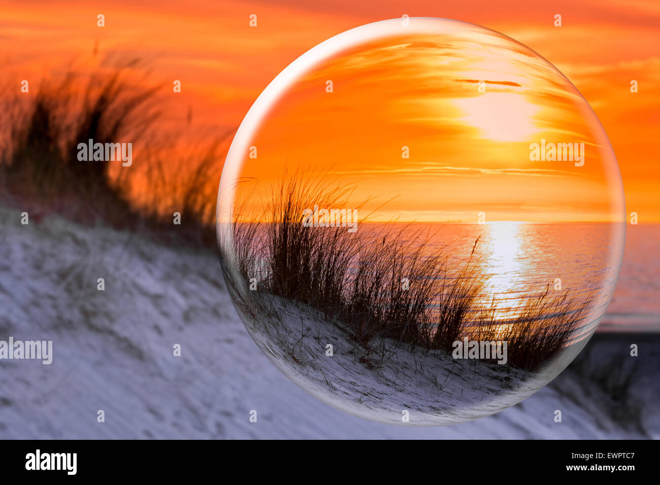 Crystal ball reflecting orange sunset at coast with sea dune and sand ...