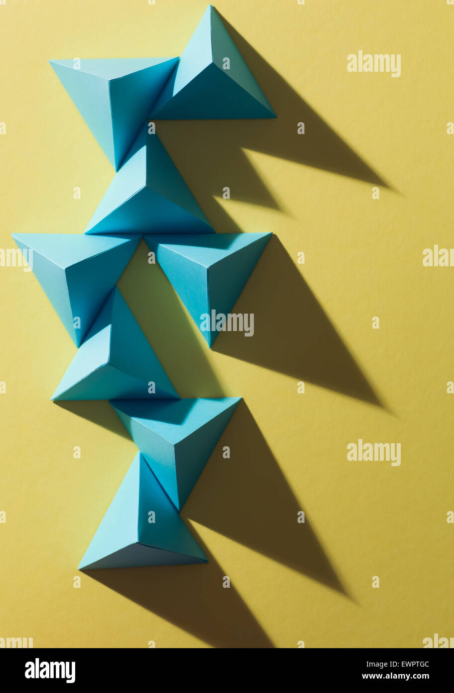 abstract construction made out of paper pyramids, with harsh shadows ...