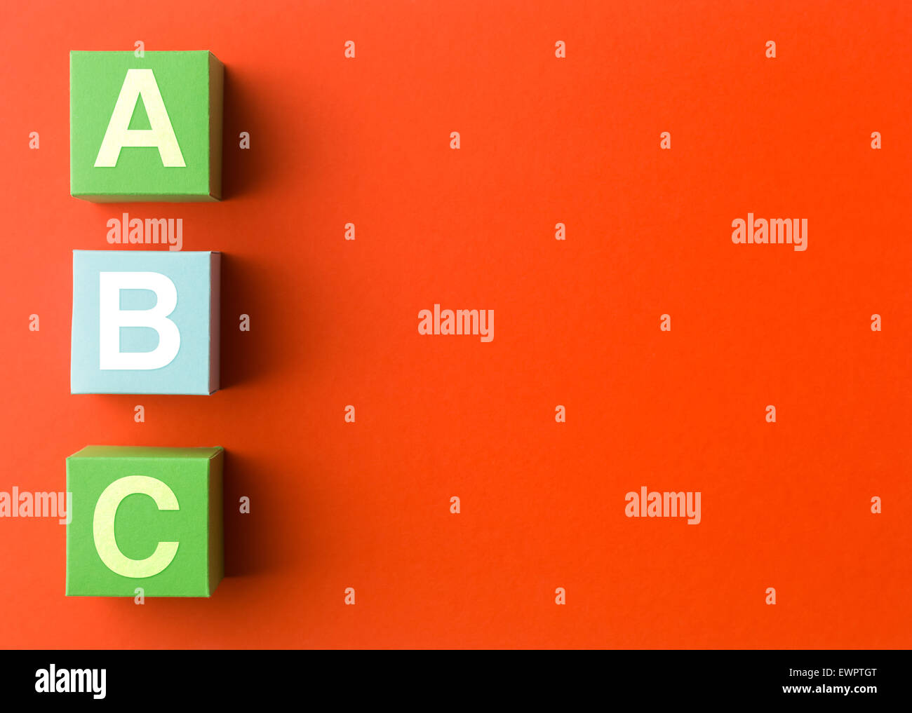 three colorful paper cubes with capital letters, in a row on red ...
