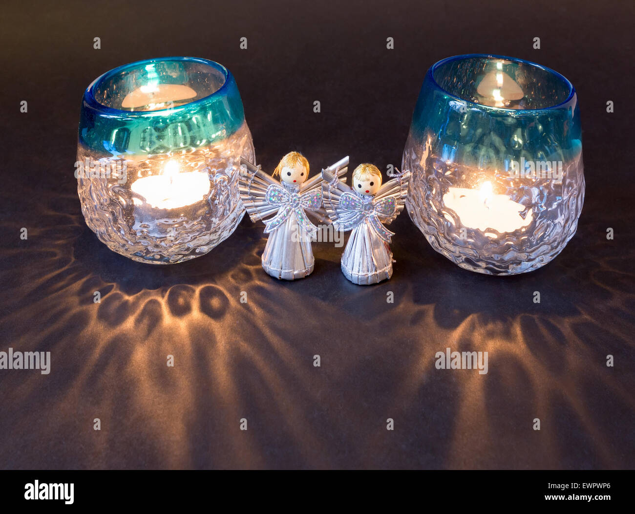 Two little angels and reflections of tea lights isolated on black ...
