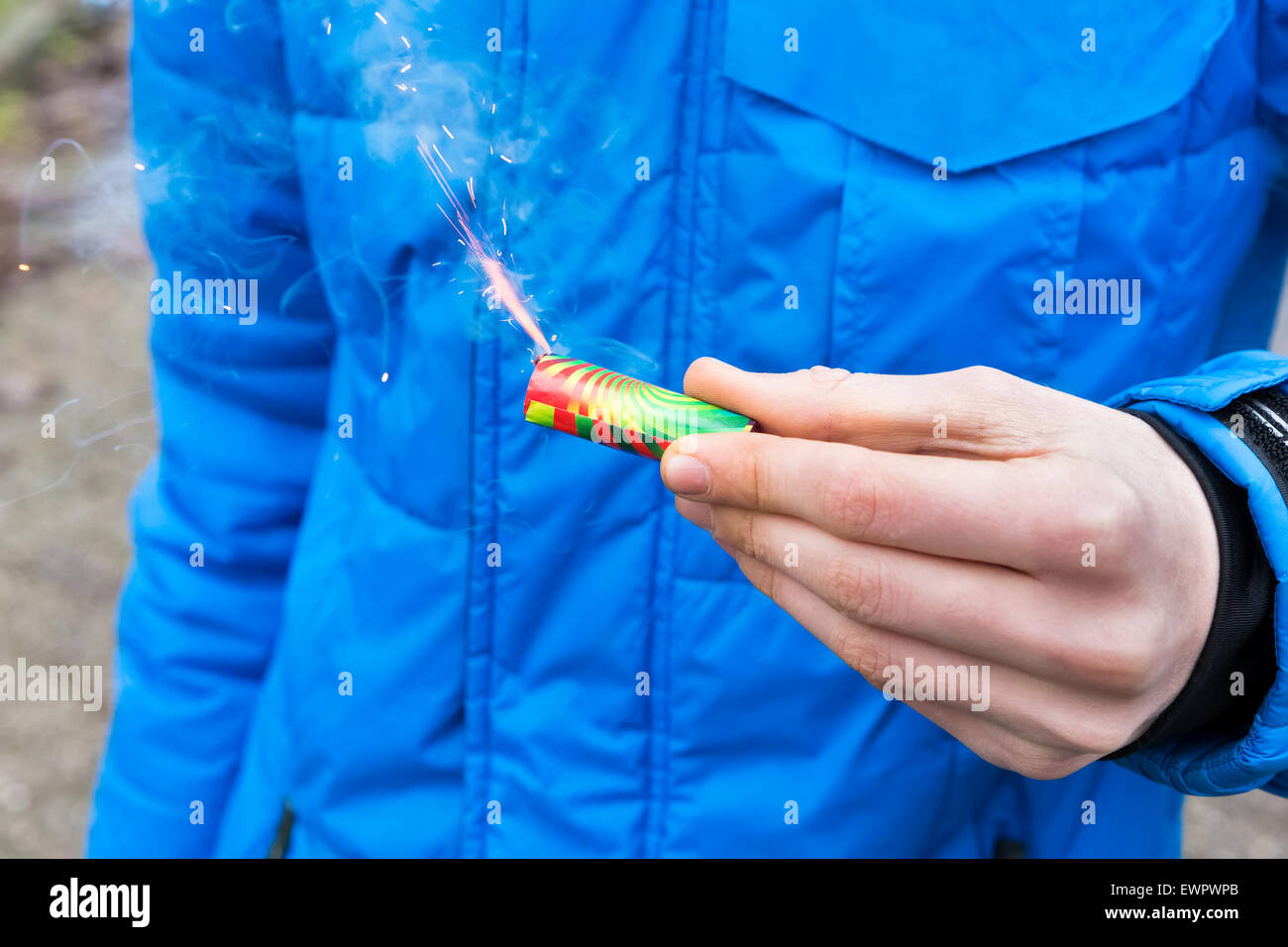 Hand of boy holding burning firework in front of blue jacket at New ...