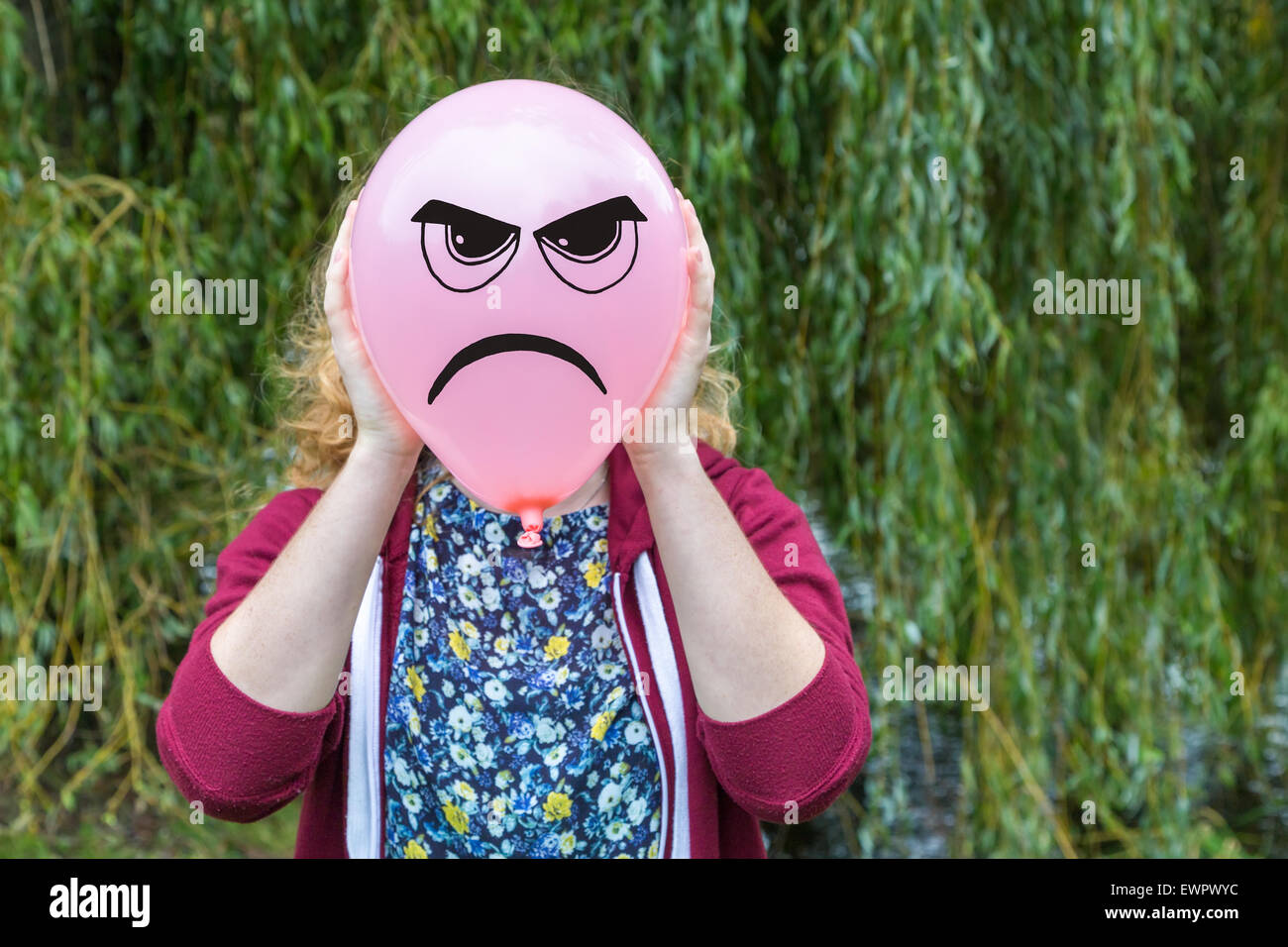 Teenage girl holding balloon with angry face as expression in nature ...