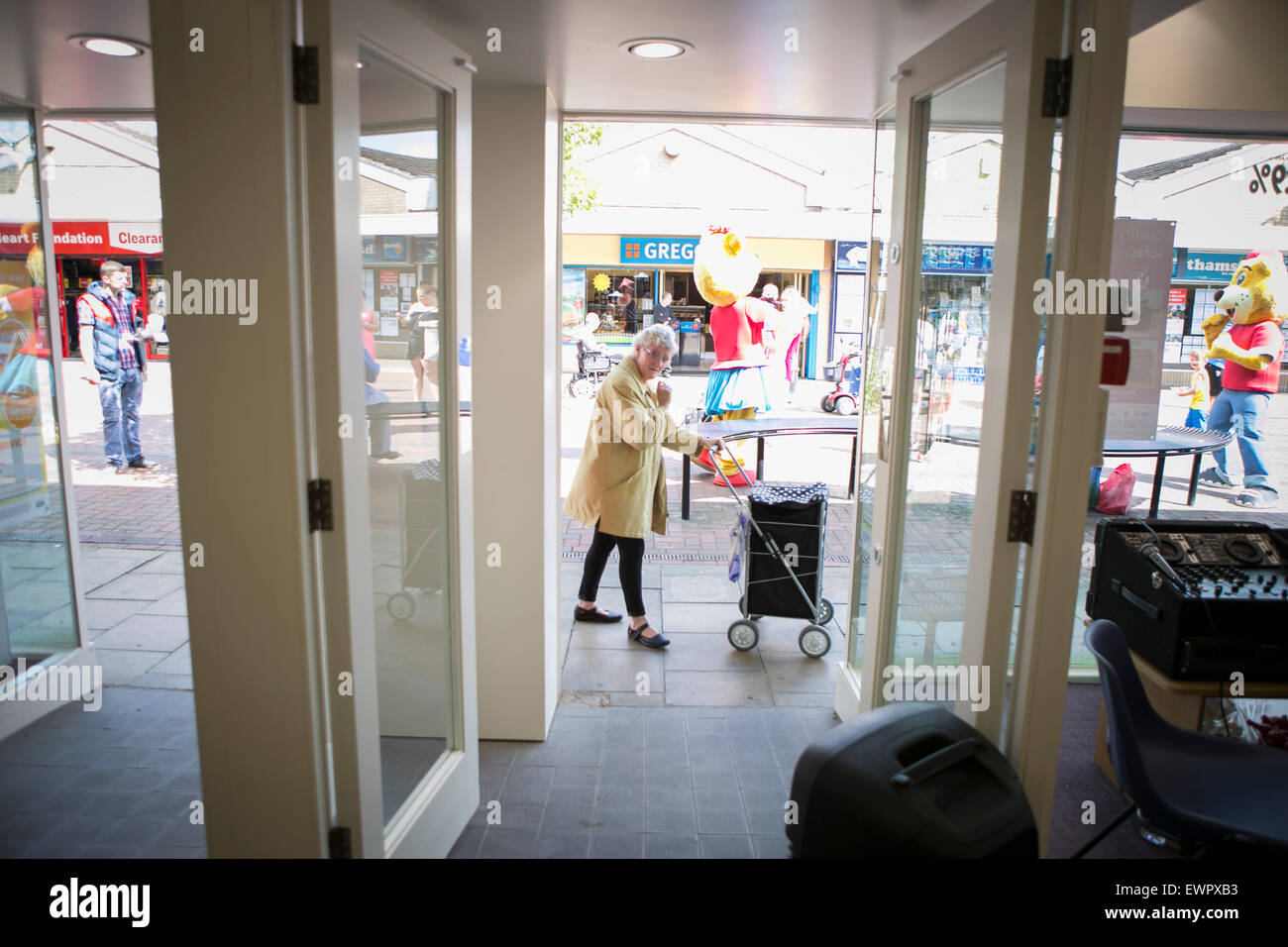 A woman with a shopping trolley walks past an open shop door Stock ...