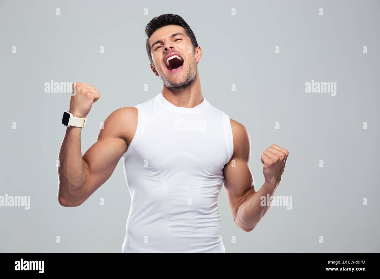 Handsome man celebrating his success over gray background Stock Photo ...