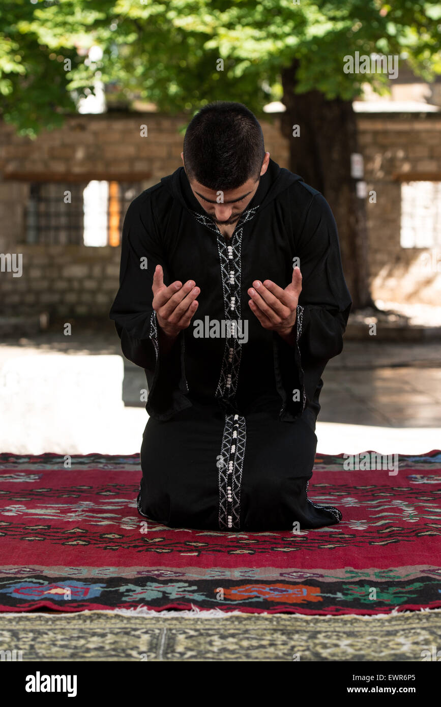 Young Muslim Man Making Traditional Prayer To God While Wearing A ...