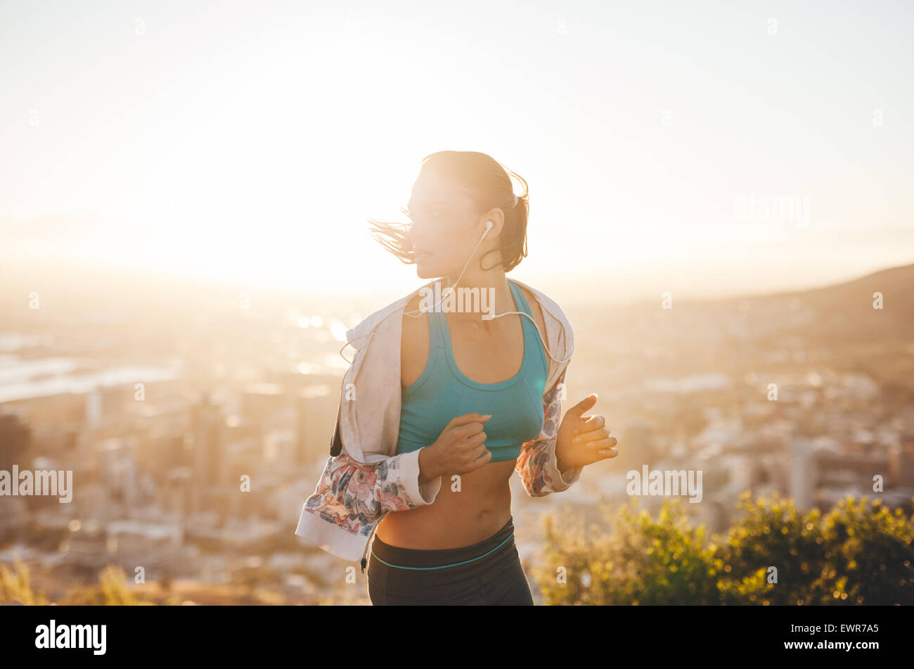 Runner training in the nature with sun behind her. Young woman running ...