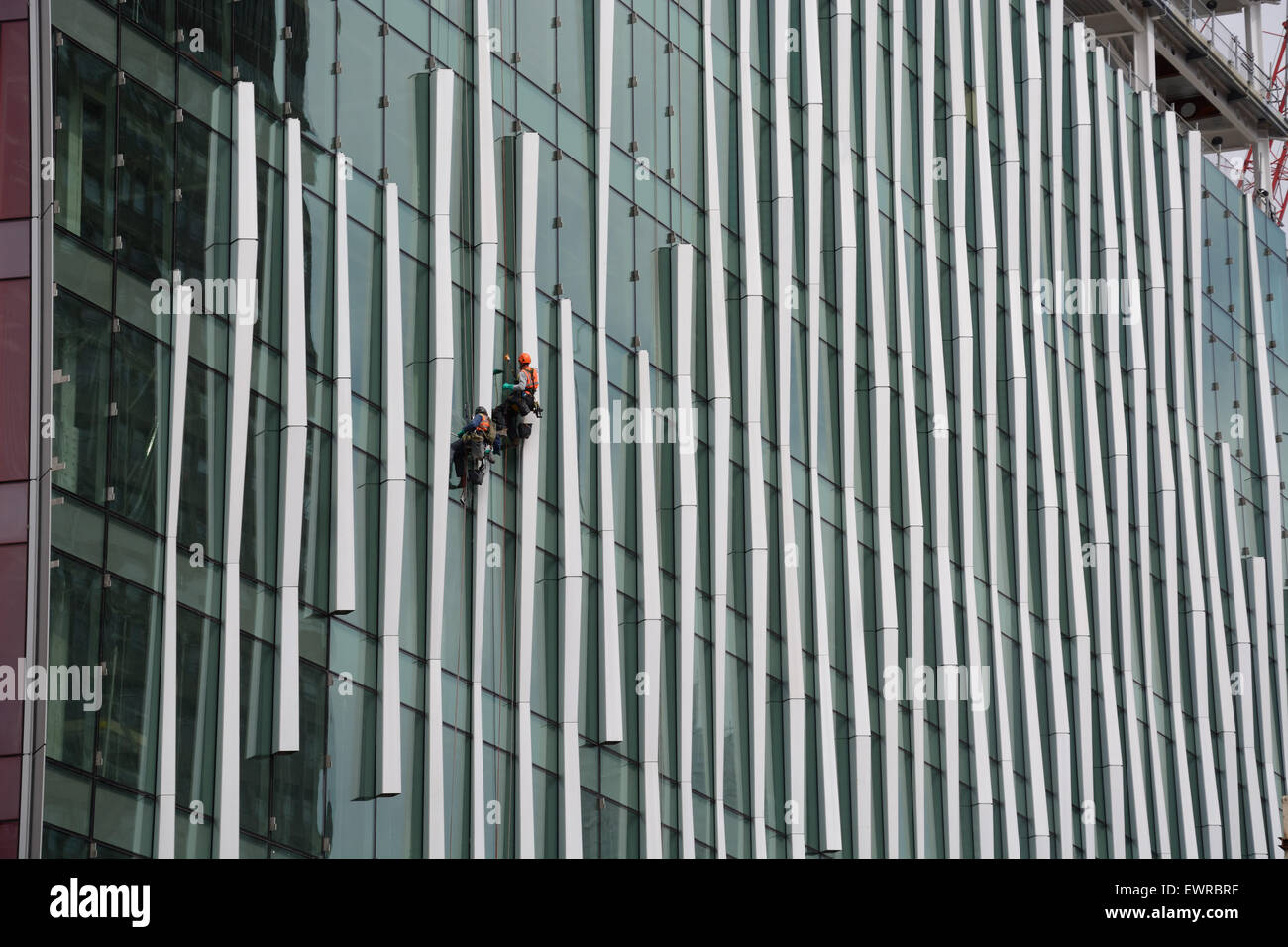Worker on rope, cladding new building at Victoria, London. England ...