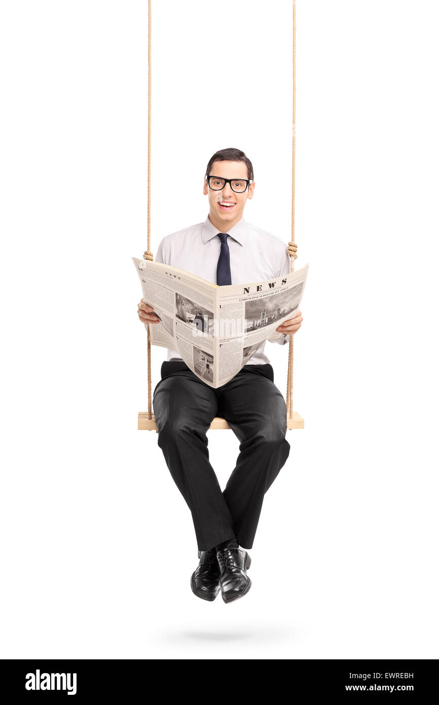 Vertical shot of a young man reading a newspaper seated on a swing and ...