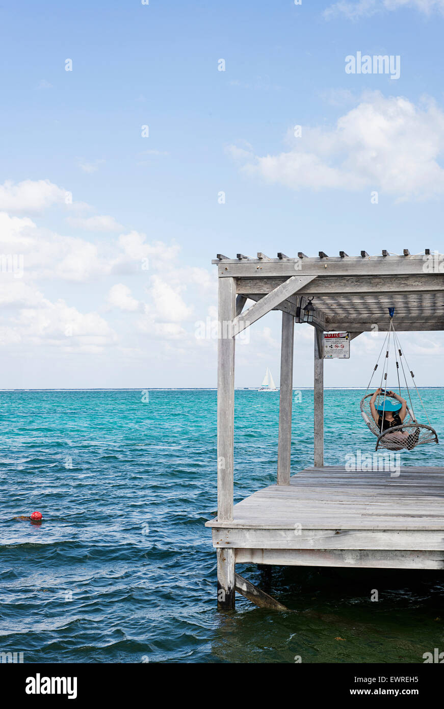 A woman hanging out on a dock in Belize with a boat sailing by in the ...